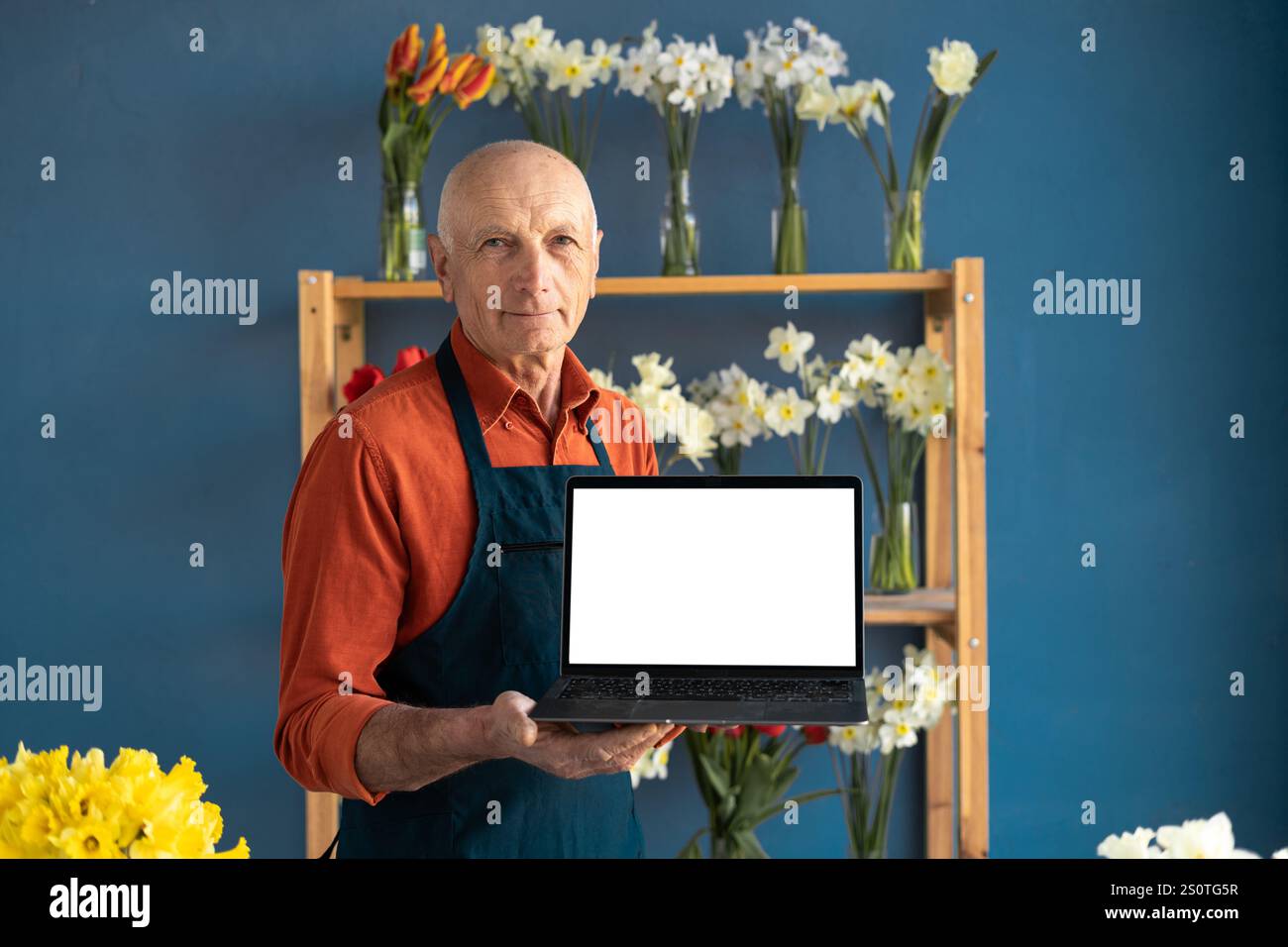 European male florist, owner of a small flower shop, works on a laptop ...