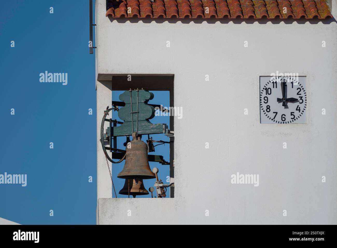Church tower with clock and bell against a clear blue sky, showcasing ...