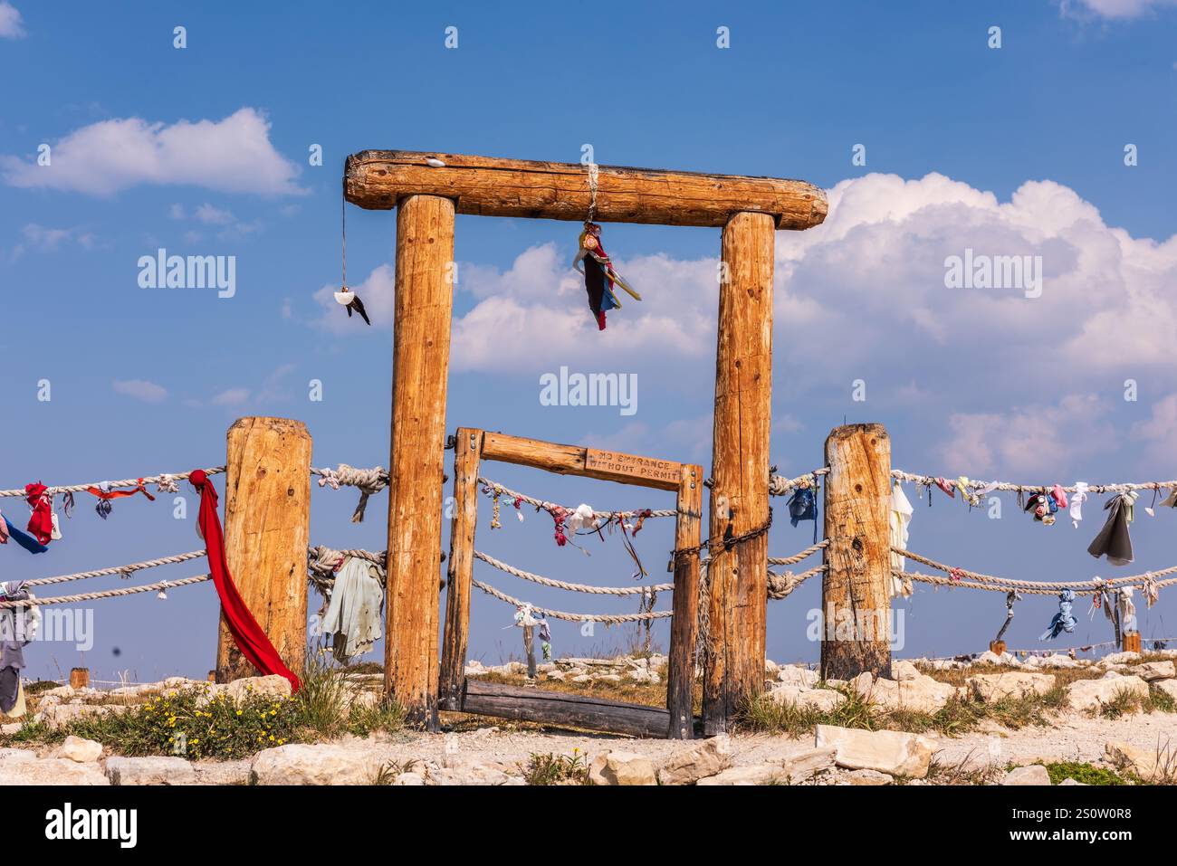Prayer offerings hang from the post and rope fence surrounding the ...