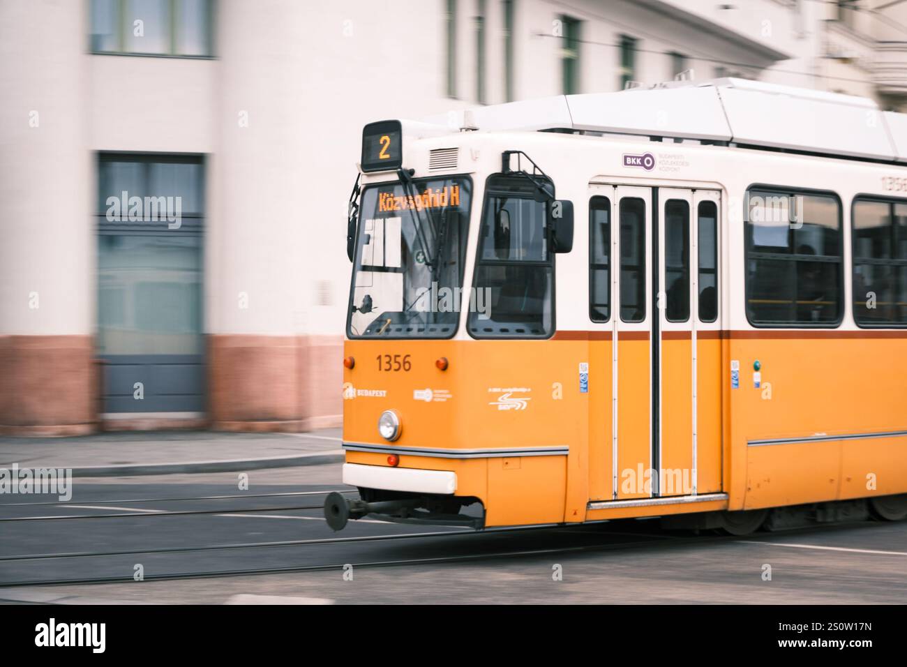 A yellow orange colored tram rides in downtown Budapest, capital of ...
