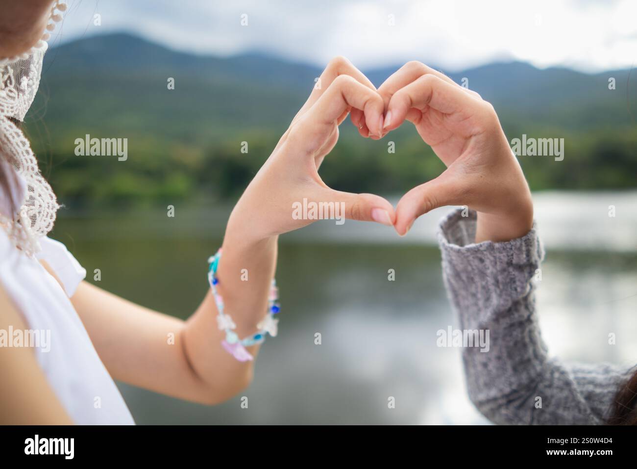 Young Asian woman raises her hands to make a heart shape to show ...