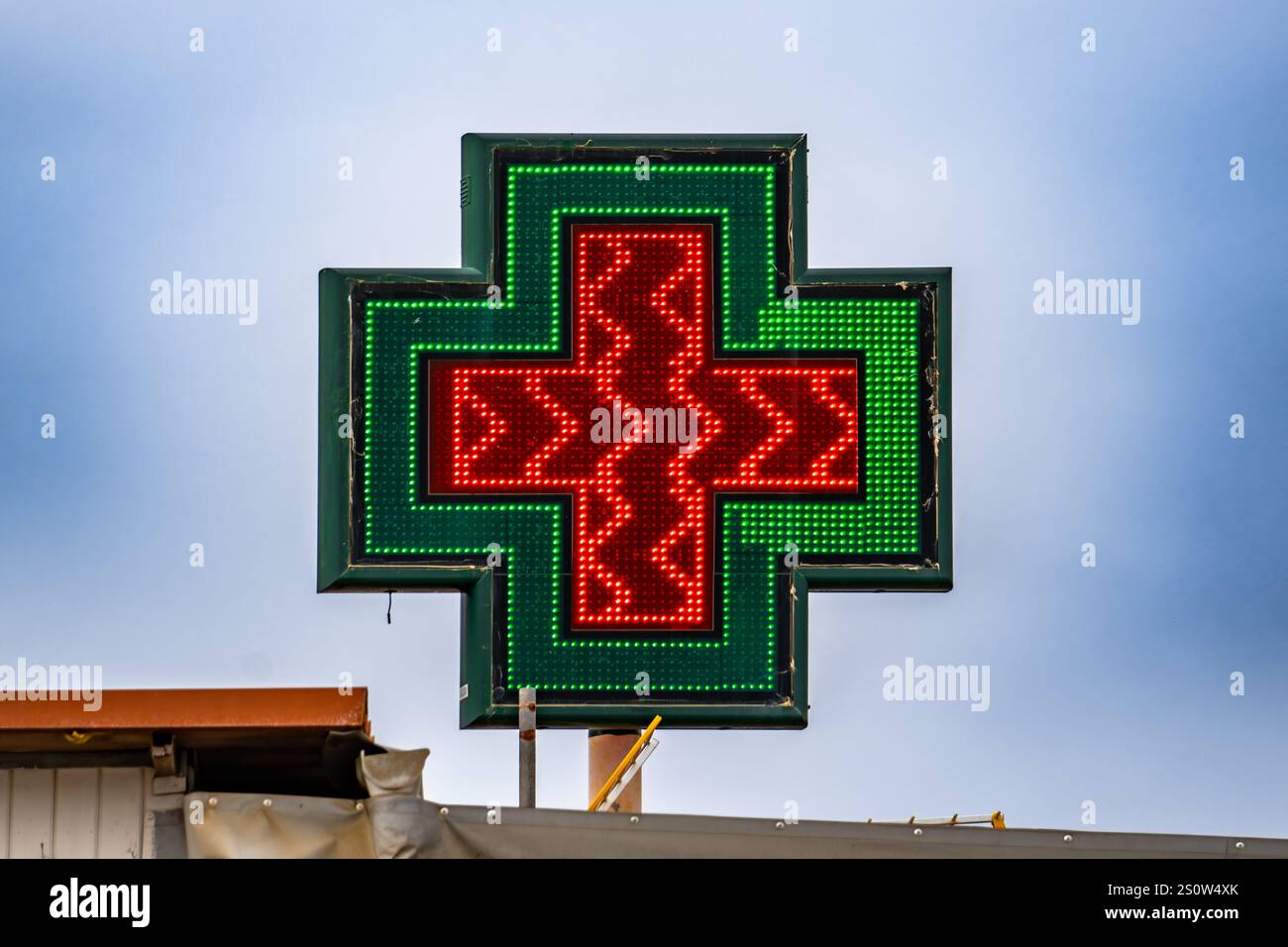 A neon sign with a green cross and red arrows. The sign is lit up and ...