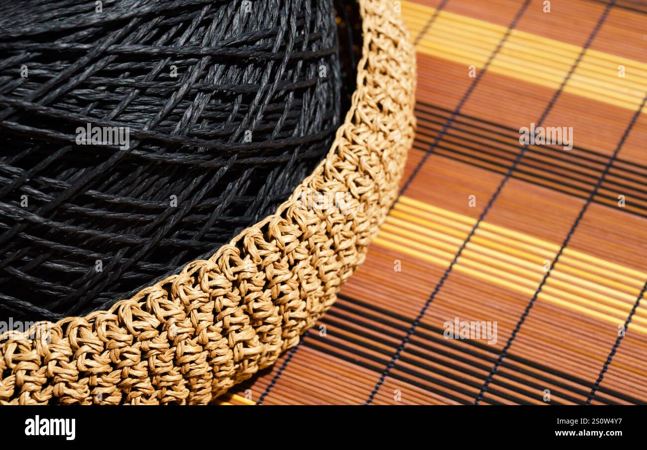 A skein of black raffia in a woven bowl of beige raffia. Handmade ...