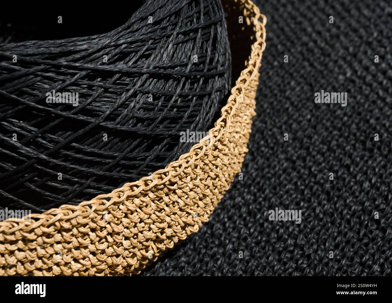 A skein of black raffia in a woven bowl of beige raffia. Handmade ...