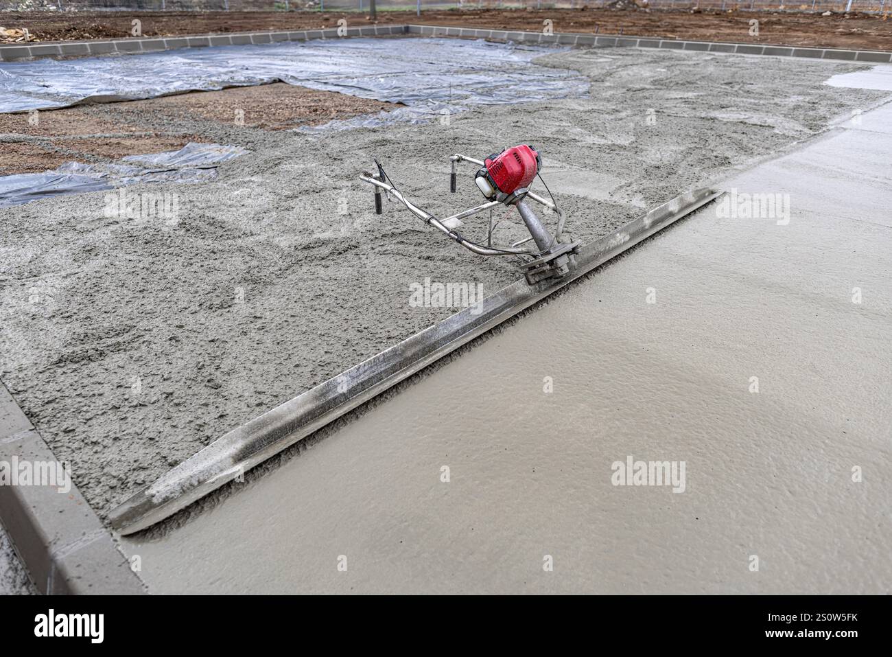 Power screed smoothing fresh concrete surface at construction site with ...