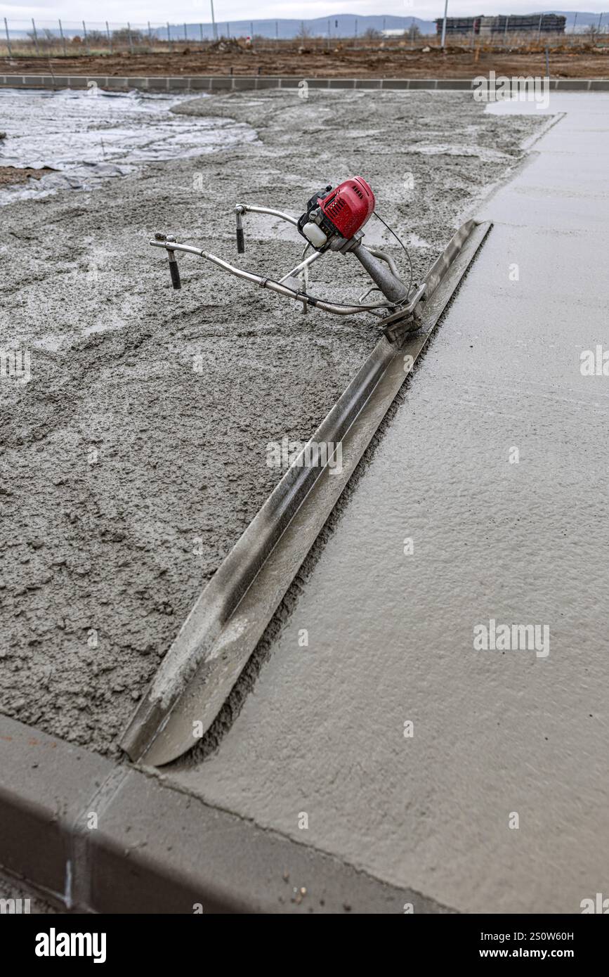 Power screed smoothing fresh concrete surface at construction site with ...