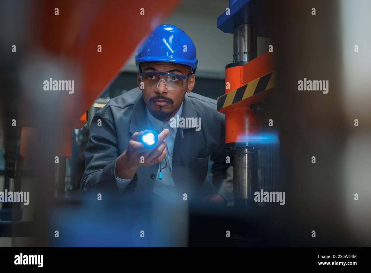 African American maintenance engineer in an industry plant, carefully ...