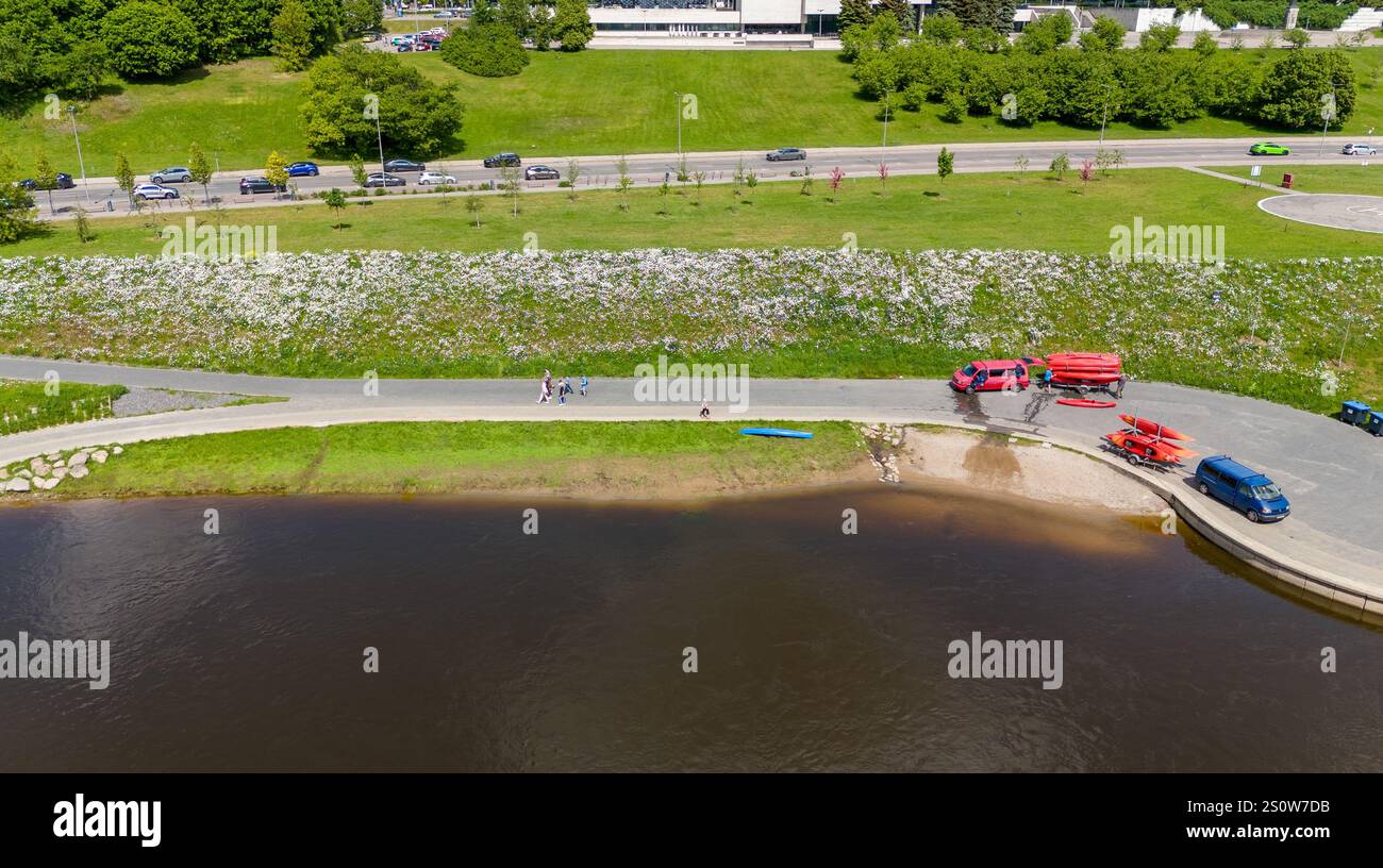 Aerial view of a riverside park with a walking path, green grass, and ...