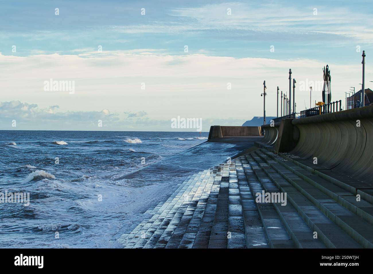 Coastal seawall with stepped access, extending from a shoreline with ...