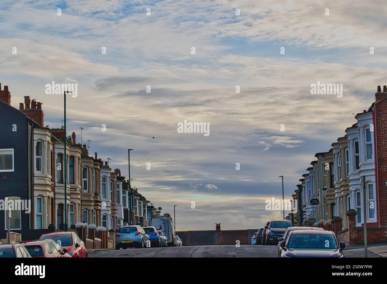 Residential street scene showing rows of terraced houses under a cloudy ...
