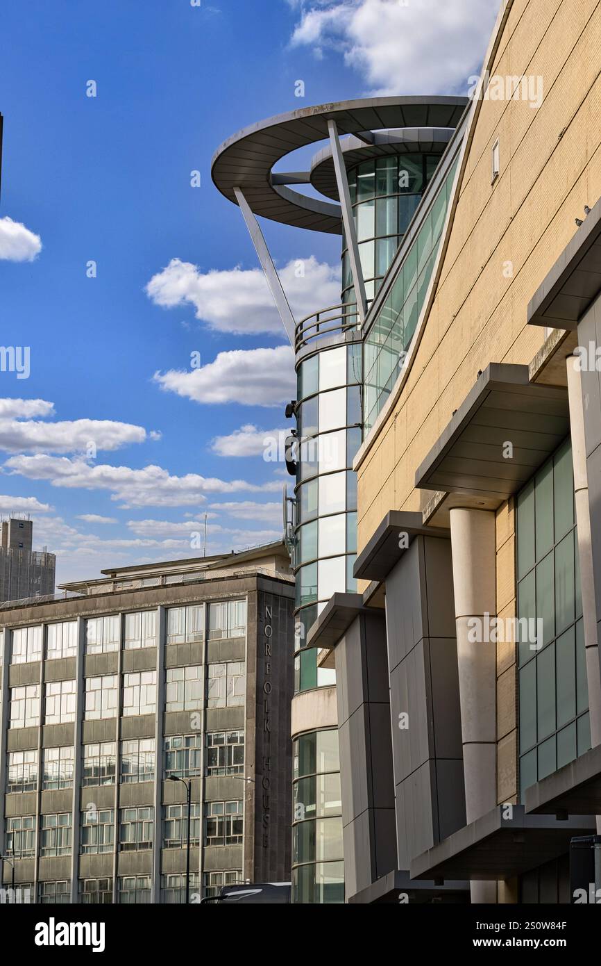 Modern and older buildings stand adjacent under a partly cloudy blue ...