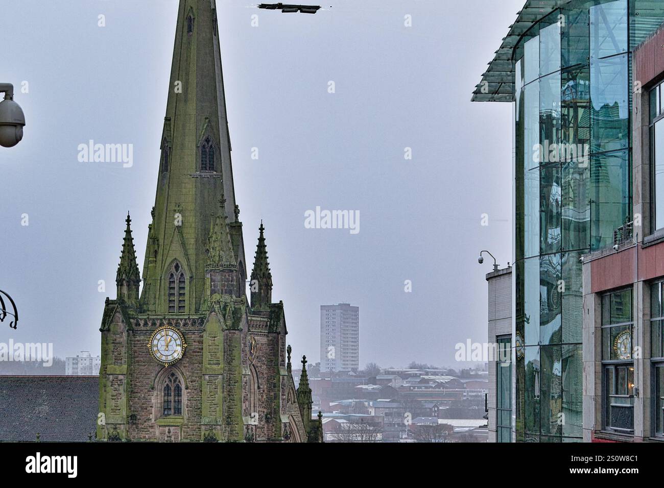 A tall church spire, partially covered in green lichen, dominates the ...
