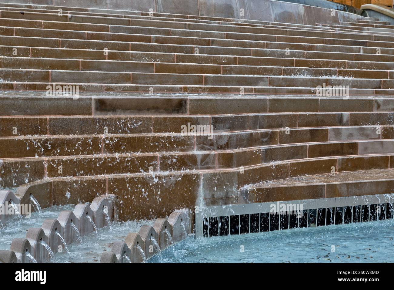 Stone steps cascading water into a pool. Brown stone steps form a ...