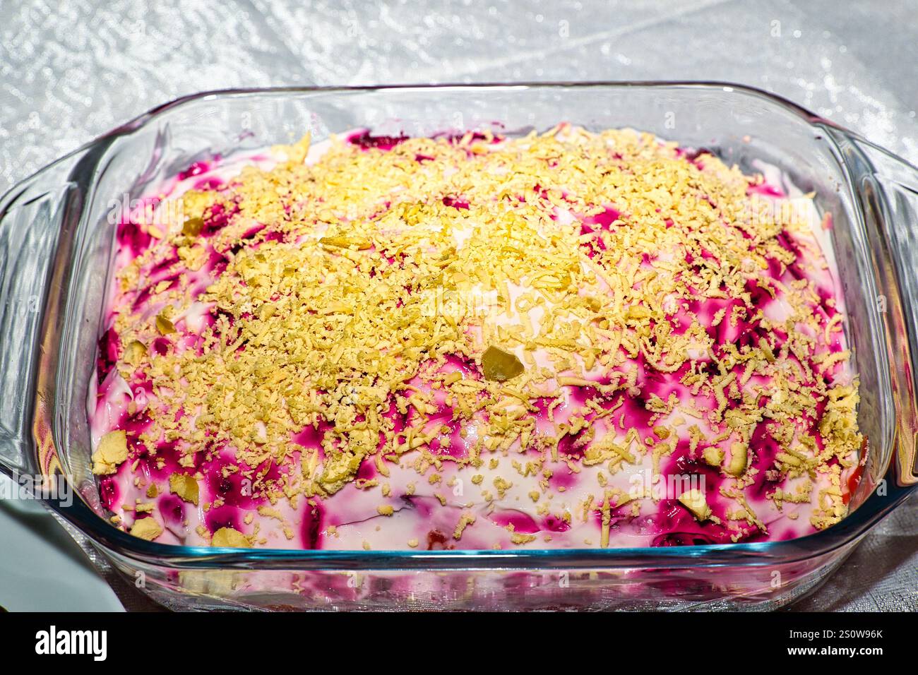 A glass baking dish contains a layered salad with a creamy pink base ...
