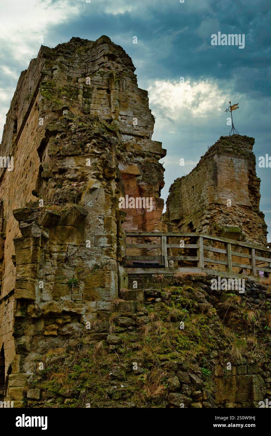 Partially ruined stone castle wall section with a wooden railing and a ...
