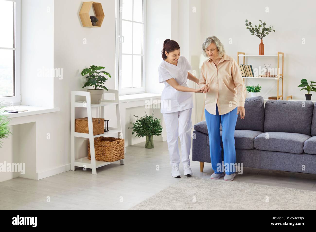 Doctor Helping Senior Woman Walk During Rehabilitation At Home Stock ...
