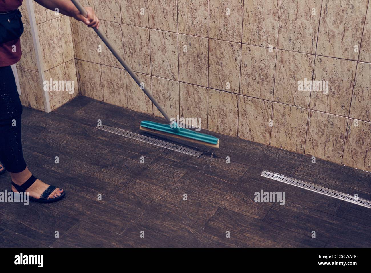A woman cleans a tiled floor with a mop, top view. Place for the text ...