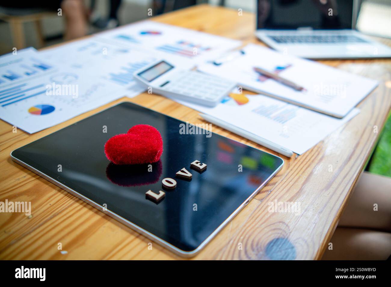 Red heart symbol placed on screen glass of tablet placed on the desk ...