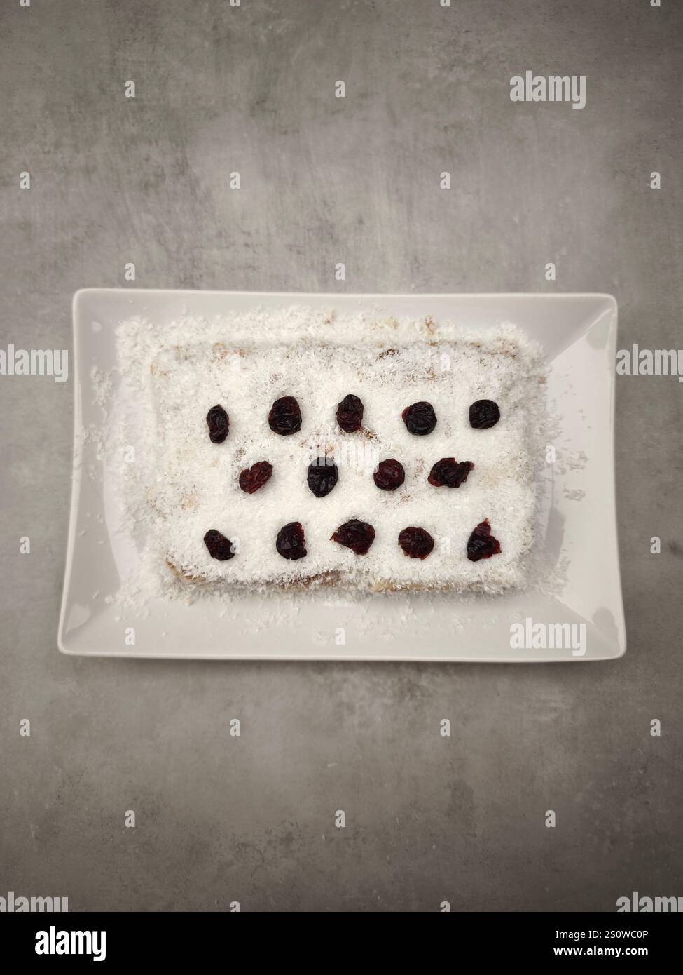 Rectangular christmas coconut pudding with cherries on top, served on a ...