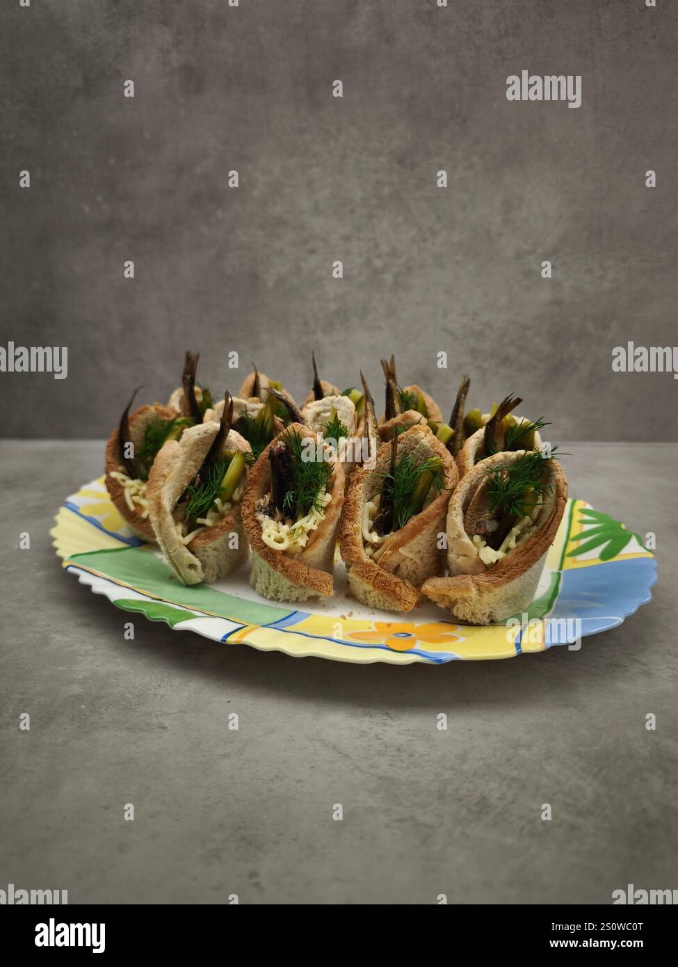 Small fish canapes with sprats, dill, gherkins, and cheese, arranged on ...