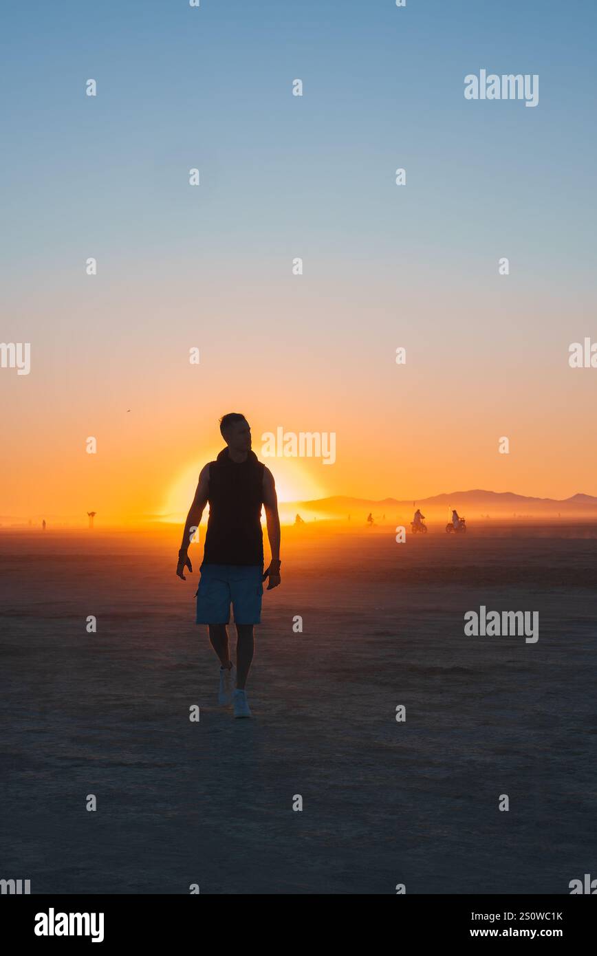 Silhouette of Person Walking at Sunset in Desert Festival Setting Stock ...