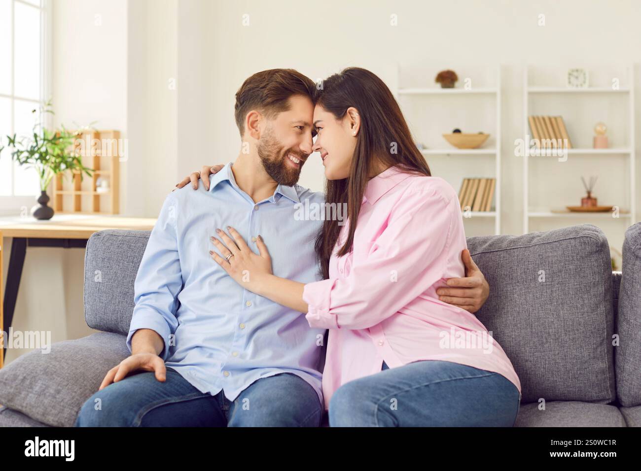 Love couple man and woman sitting on couch hugging tightly smiles ...