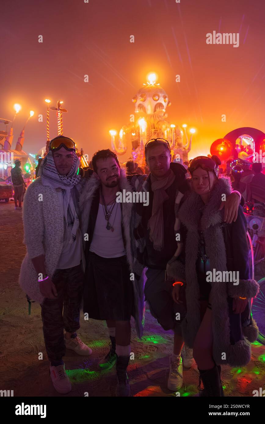 Four individuals in fur lined outfits stand before a large chandelier ...