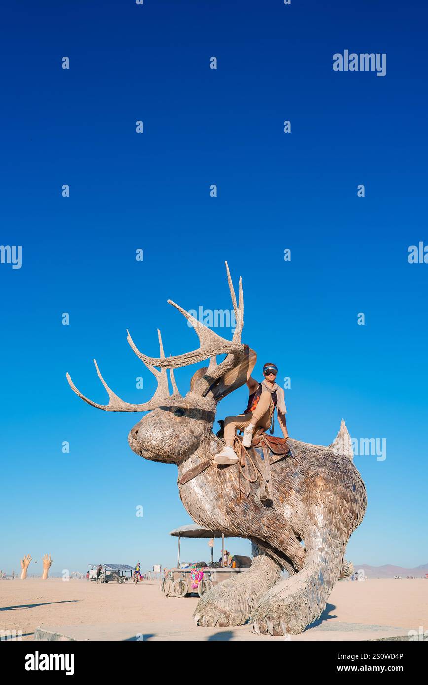 A large jackalope sculpture with a person seated on top is set in a ...