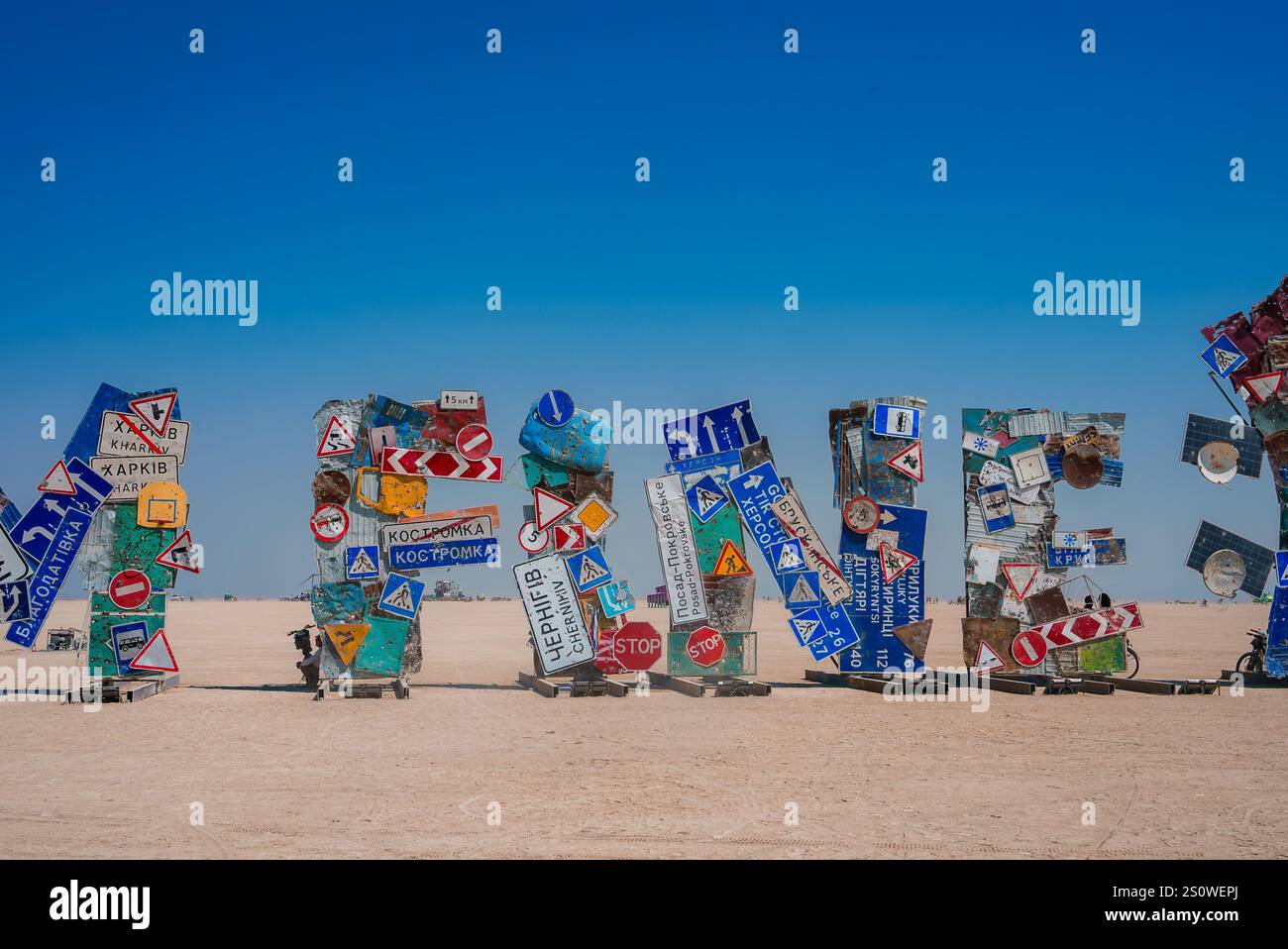 A large art installation spells 'BELIEVE' using road signs in a desert ...