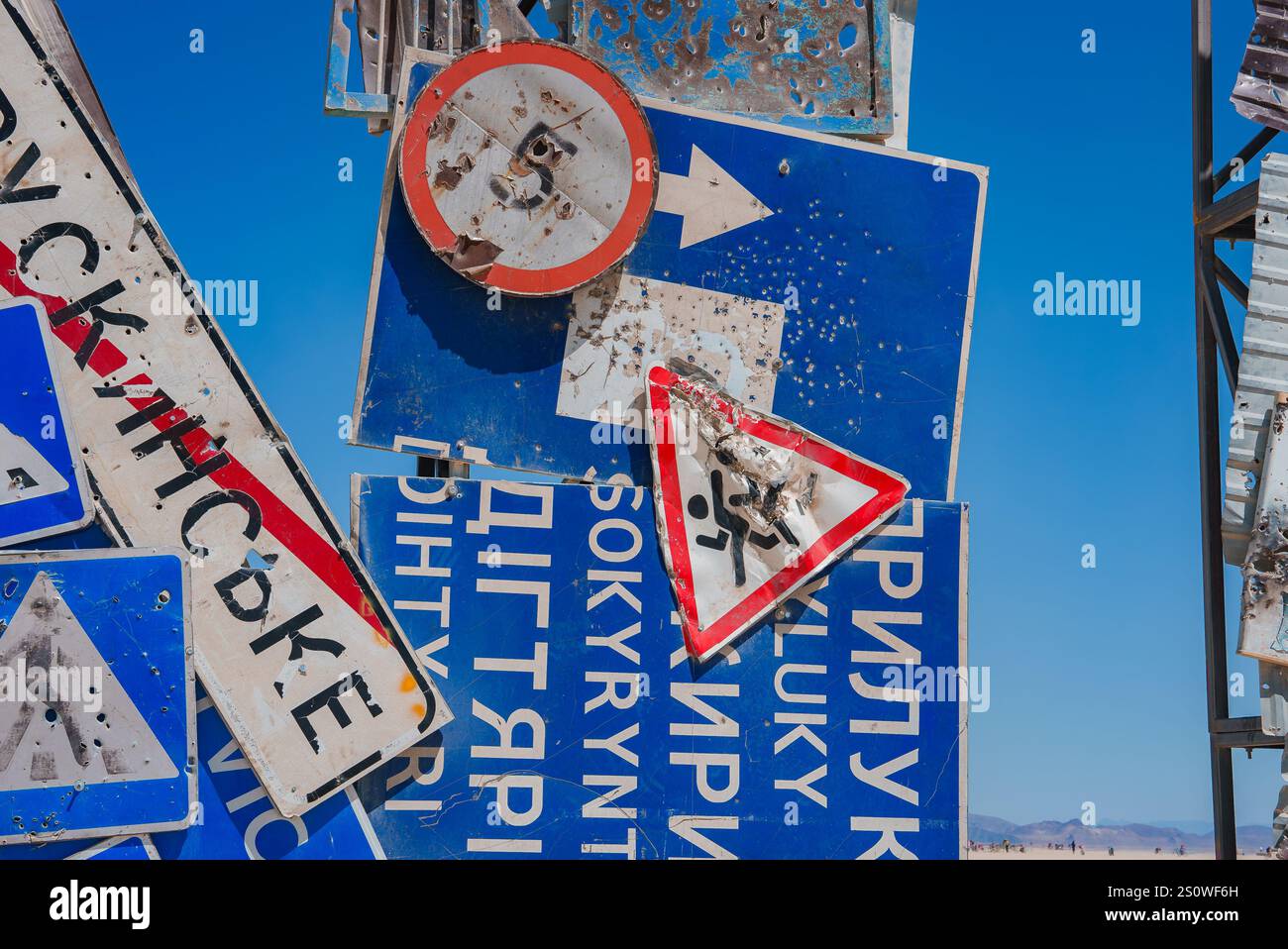 A creative assembly of road signs, some with bullet holes, set against ...