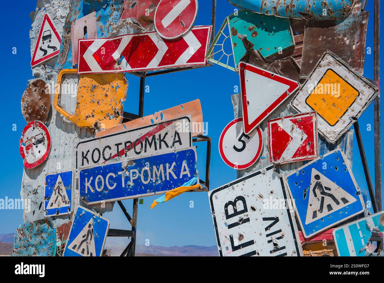 A chaotic arrangement of road signs with bullet holes on a metal ...