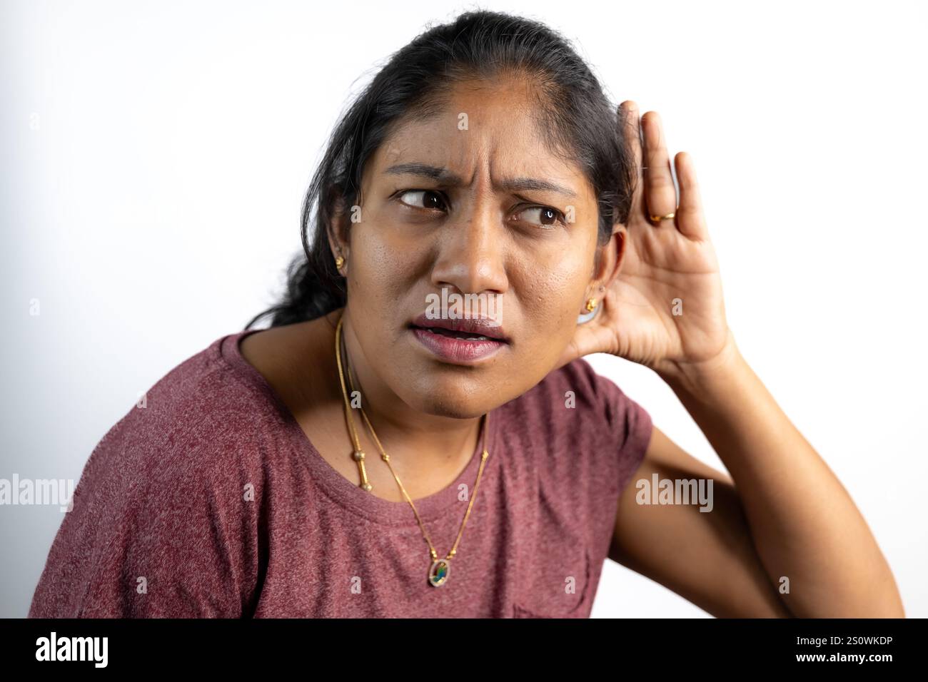 Curious woman cups her ear, straining to hear a faint sound. What secrets is she trying to ...