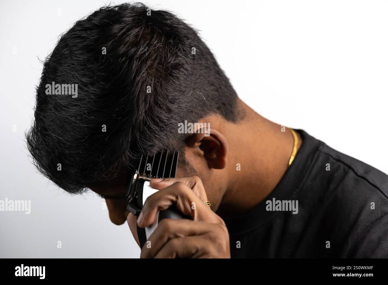 Man trimming his hair with clippers against a white background. DIY ...