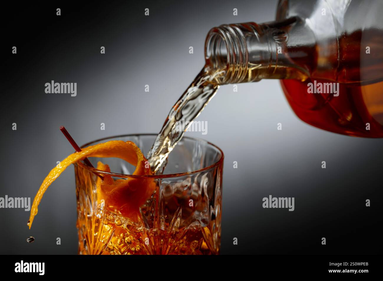 Whiskey or bourbon pouring into a crystal glass. Old-fashioned cocktail ...