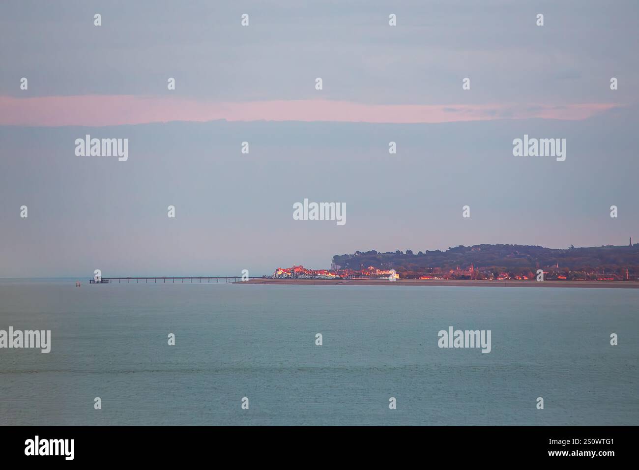 Deal pier and the buildings of Deal town lit up by the setting sun. As ...