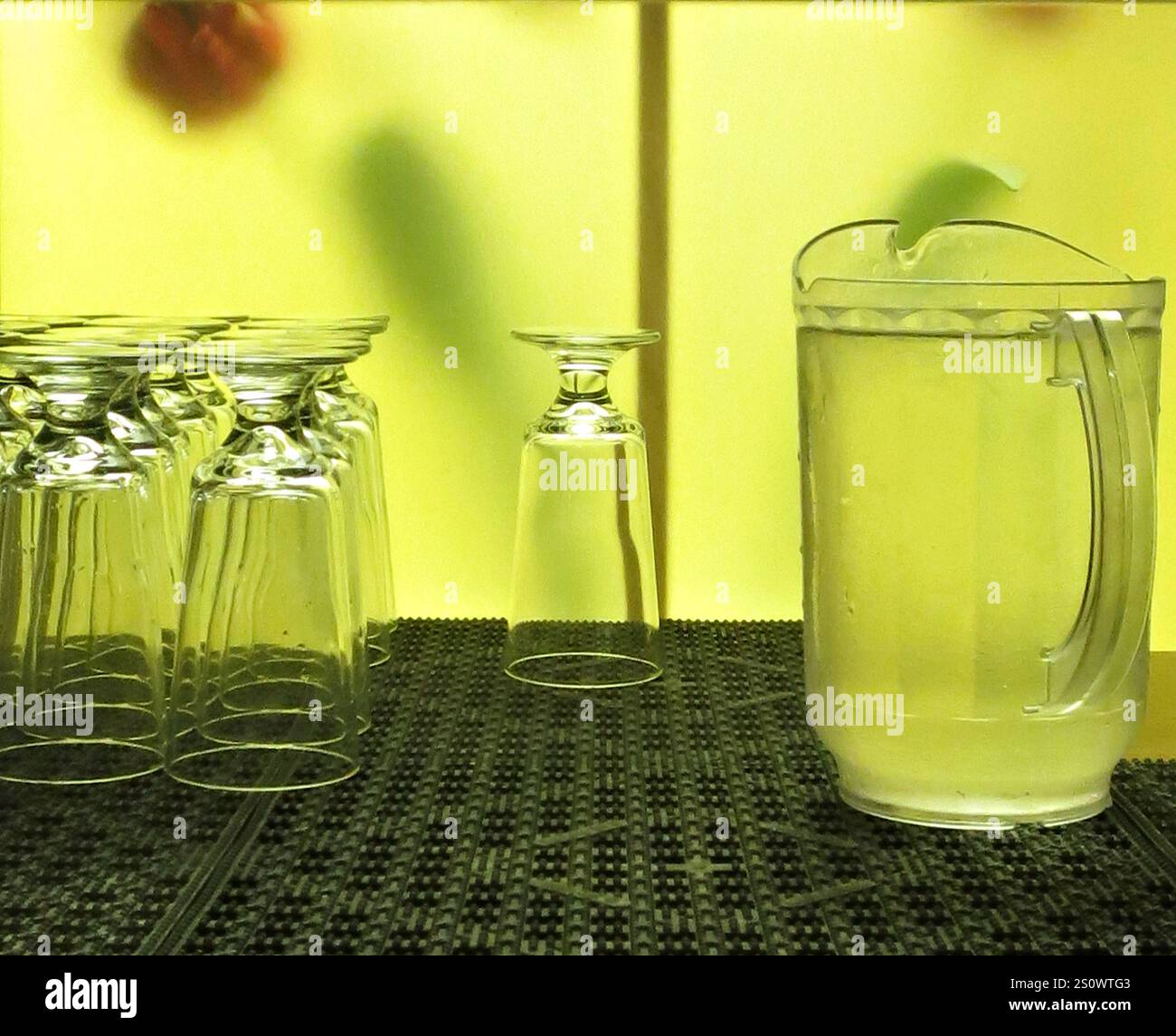 Inverted water glasses and a pitcher of water are on a table in a ...