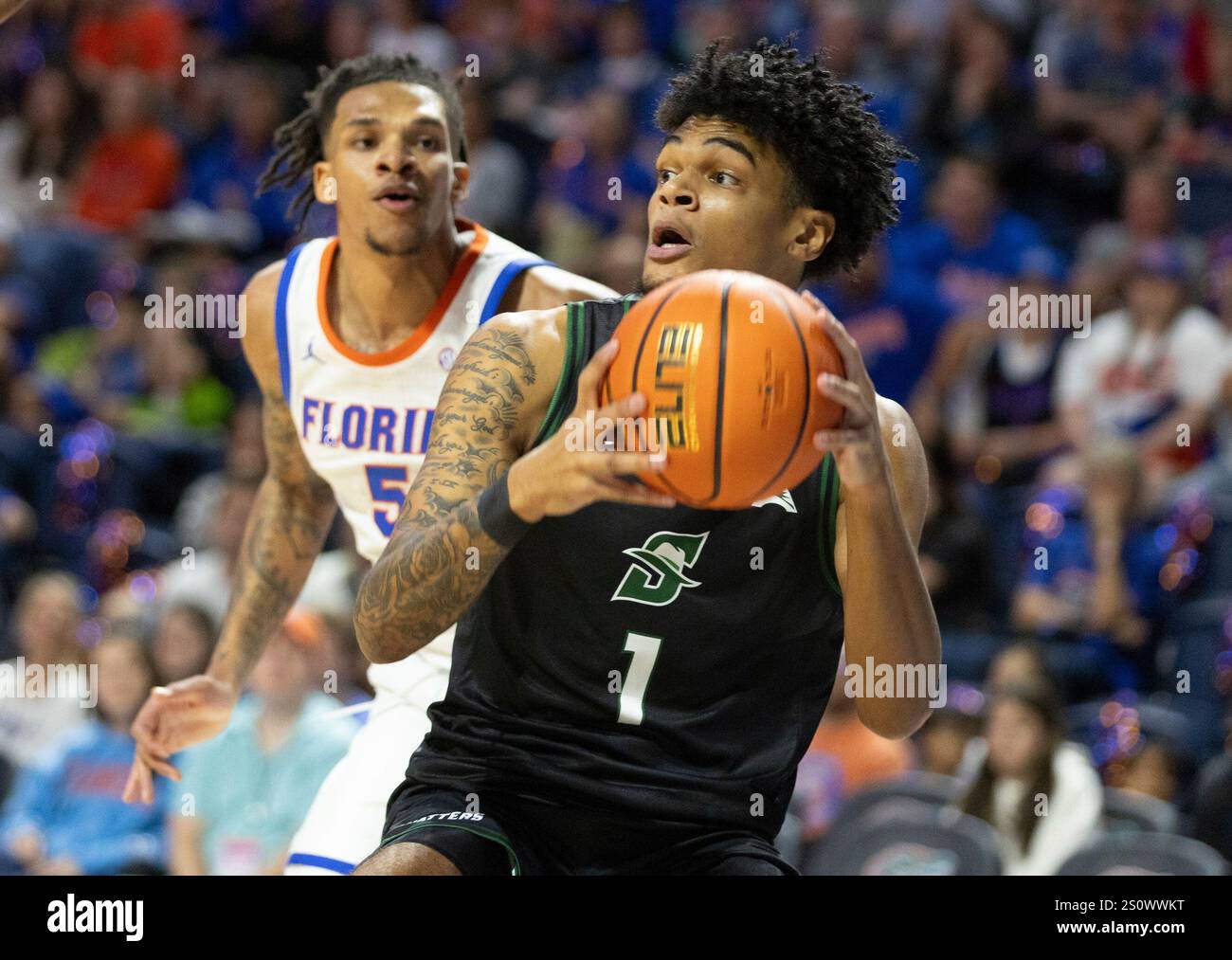 Stetson forward Josh Massey (1) drives past Florida guard Will Richard ...