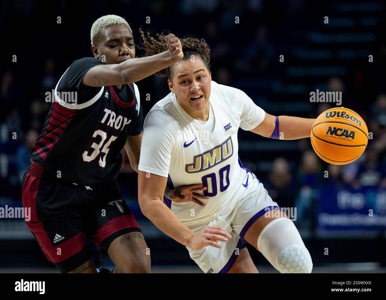 James Madison guard Peyton McDaniel (00) drives to the basket around Troy guard Leilani Guion ...