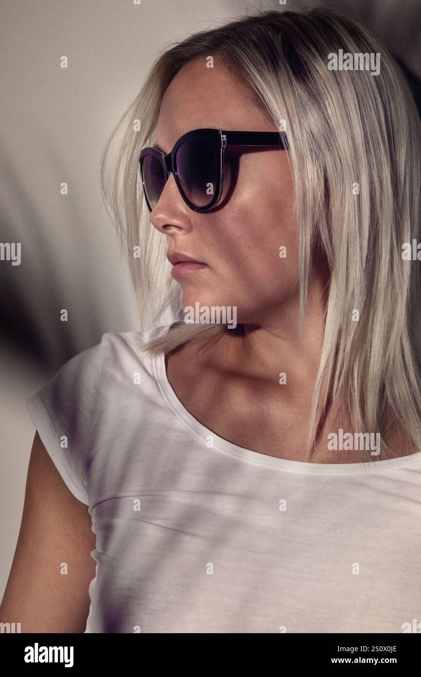Stylish woman wearing sunglasses with soft shadow overlay on a neutral ...