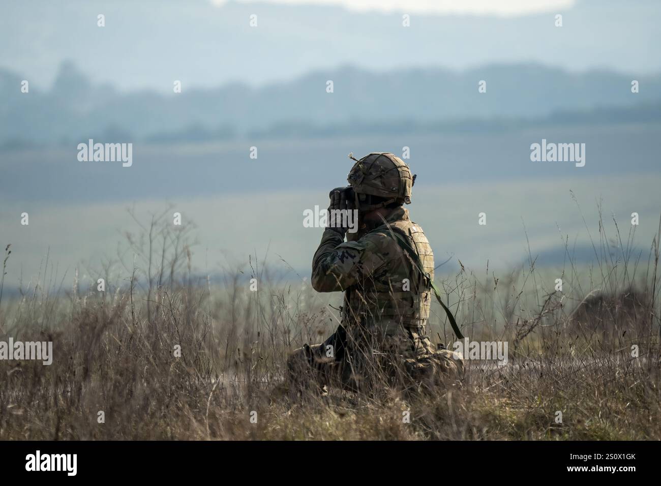 close-up of a British army infantry soldier using binoculars to scan ...