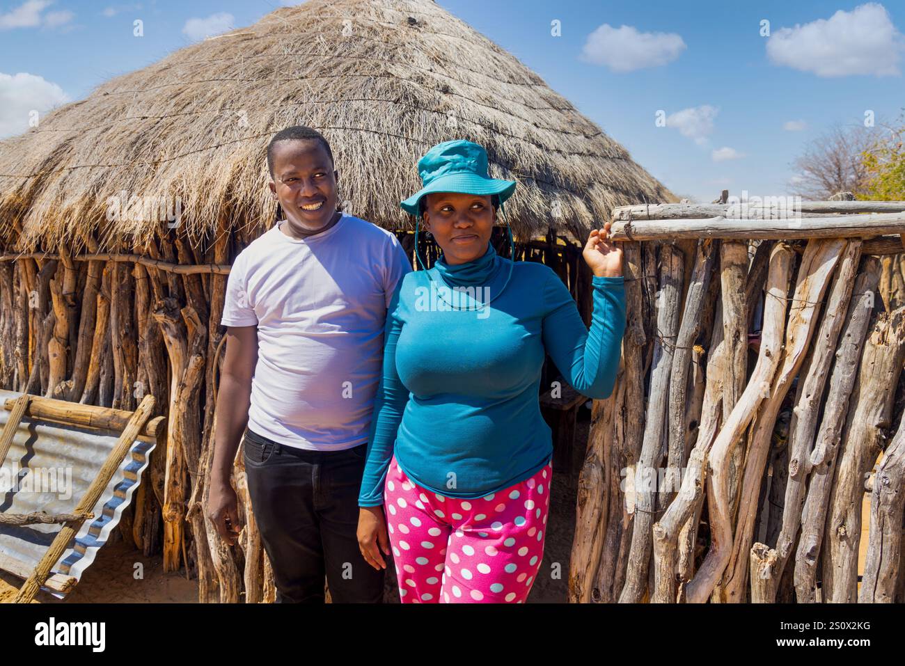 african village , happy couple husband and wife in the yard in front of the house shack with ...