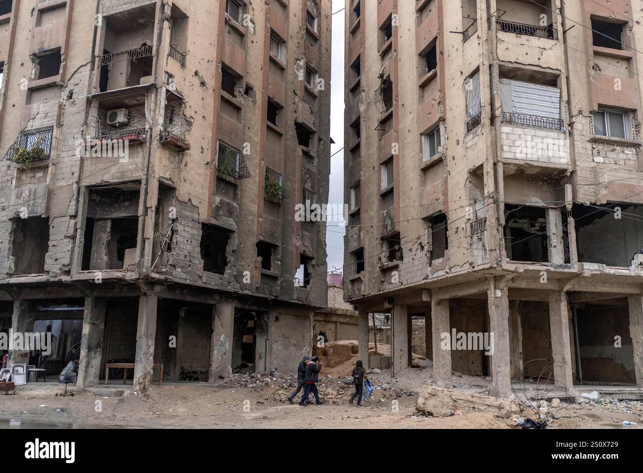 People walk between buildings that were damaged by airstrikes during ...