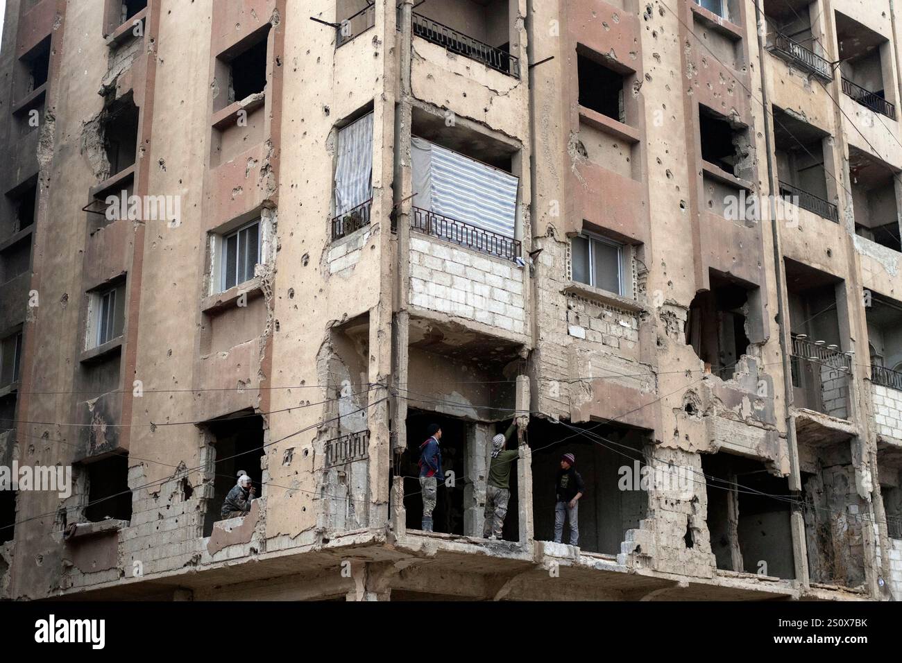 Men work in a building that was damaged by airstrikes during the Assad ...