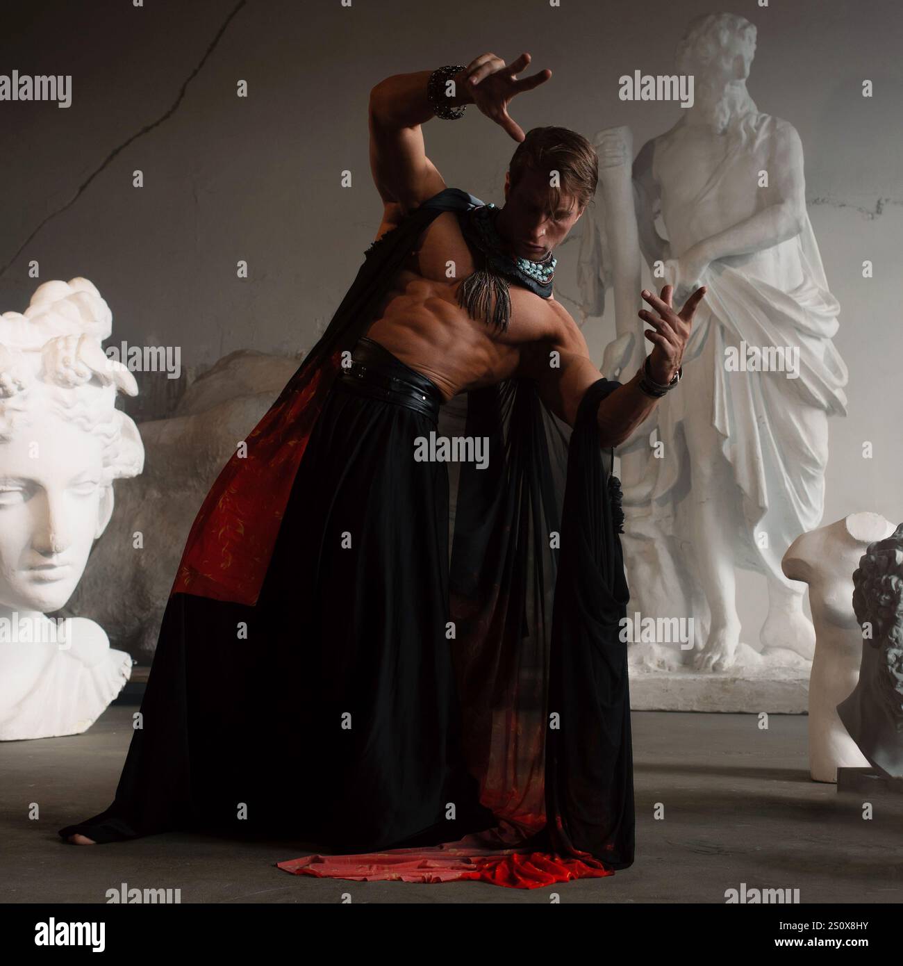 Muscular charismatic bodybuilder model in a silk cape makes an ...