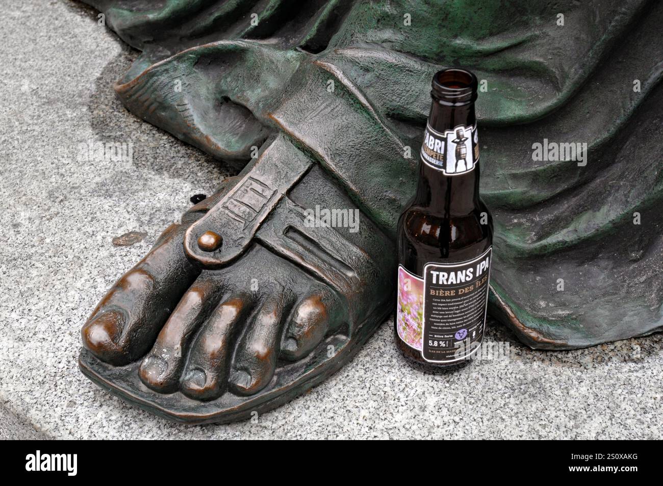 A discarded beer bottle stands beside the foot of a statue on the King ...