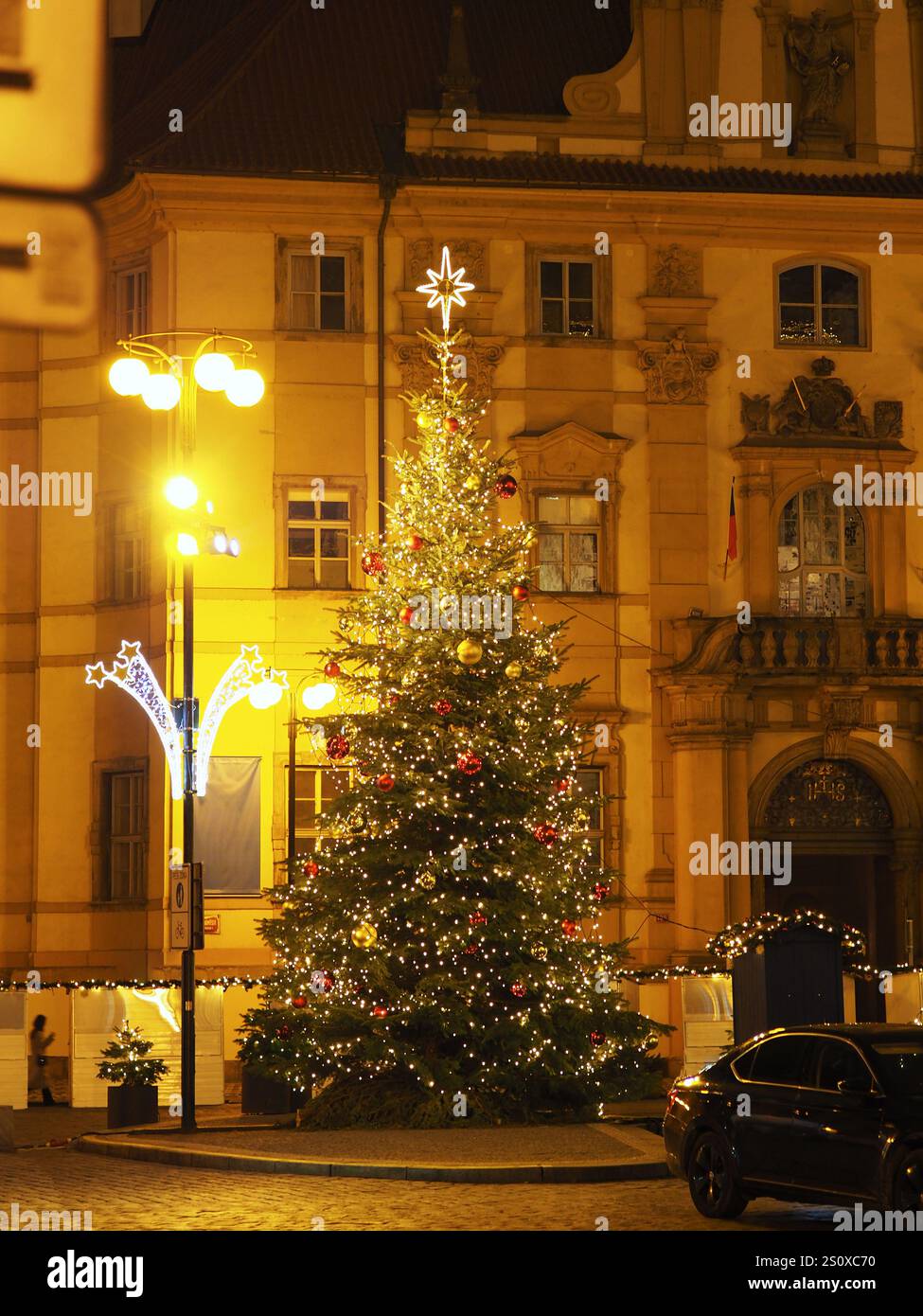 Illuminated Christmas tree in front of ornate building, with street ...
