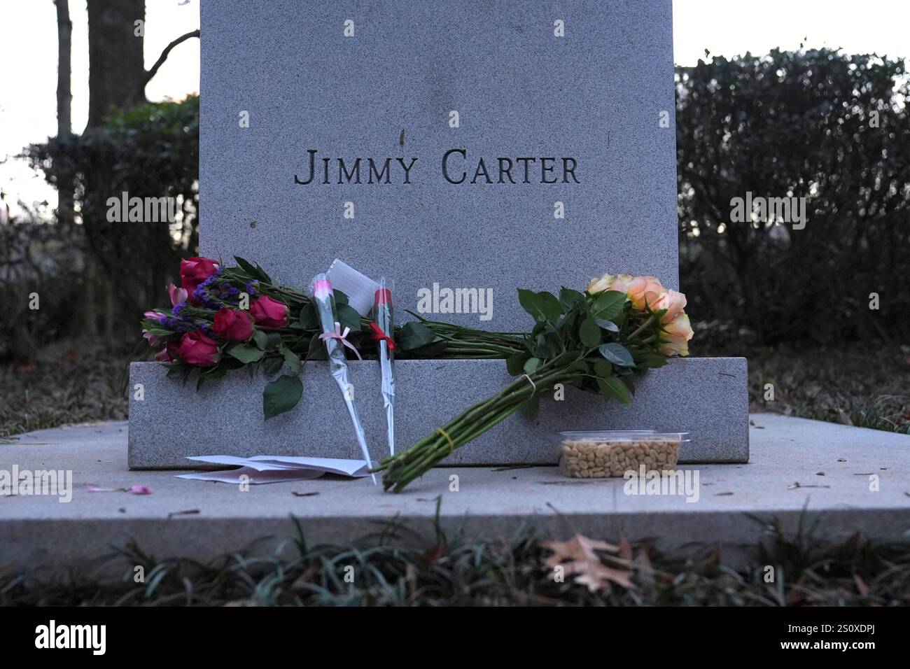 Bouquets of flowers and peanuts are placed at the base of a bust of ...