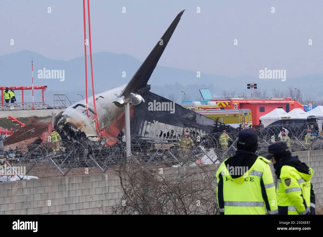 Rescue team members work at the site of a plane fire at Muan ...