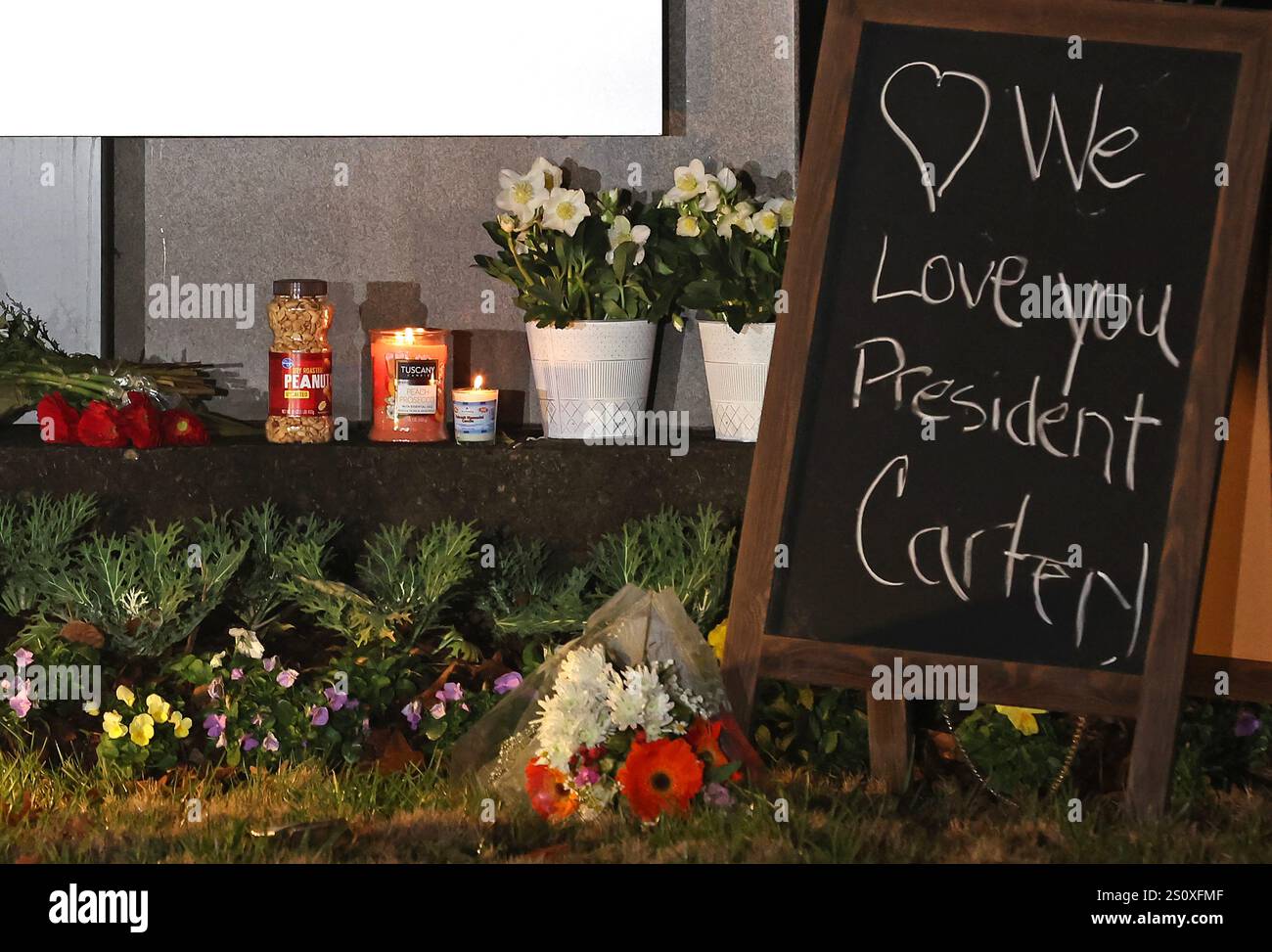 Flowers, peanuts, other goods, and signs are left at the main entrance ...