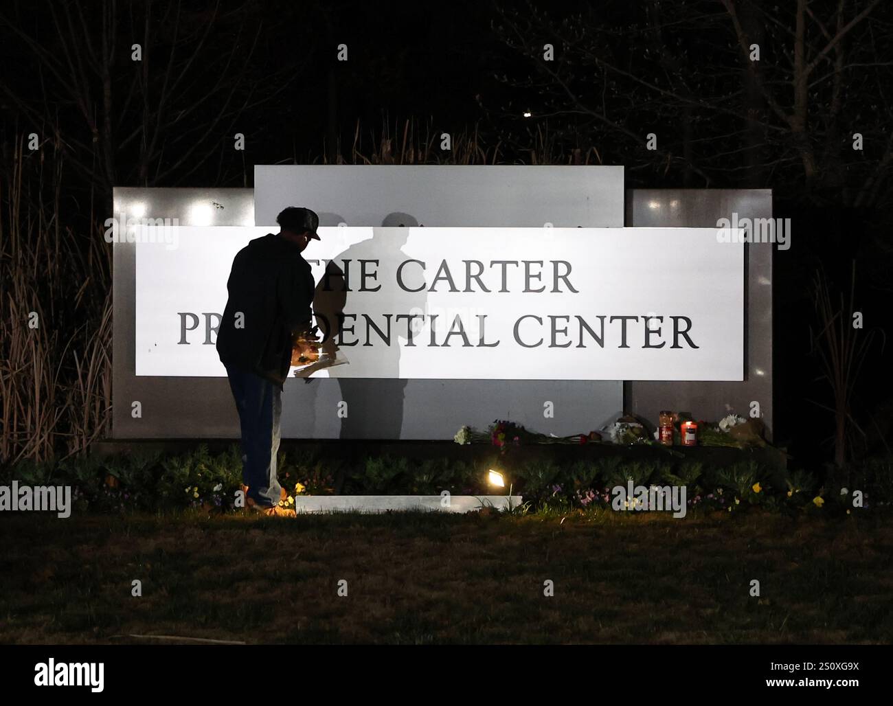 A passerby leaves flowers as a memorial at the main entrance to The ...
